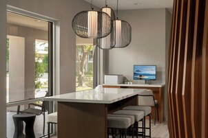 Uma cozinha moderna com uma ilha grande, iluminação pendente e uma televisão de tela plana exibindo 'Marriott Bonvoy'.