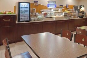 Uma área de buffet com um refrigerador, uma máquina de café e uma placa indicando o início da fila expressa.