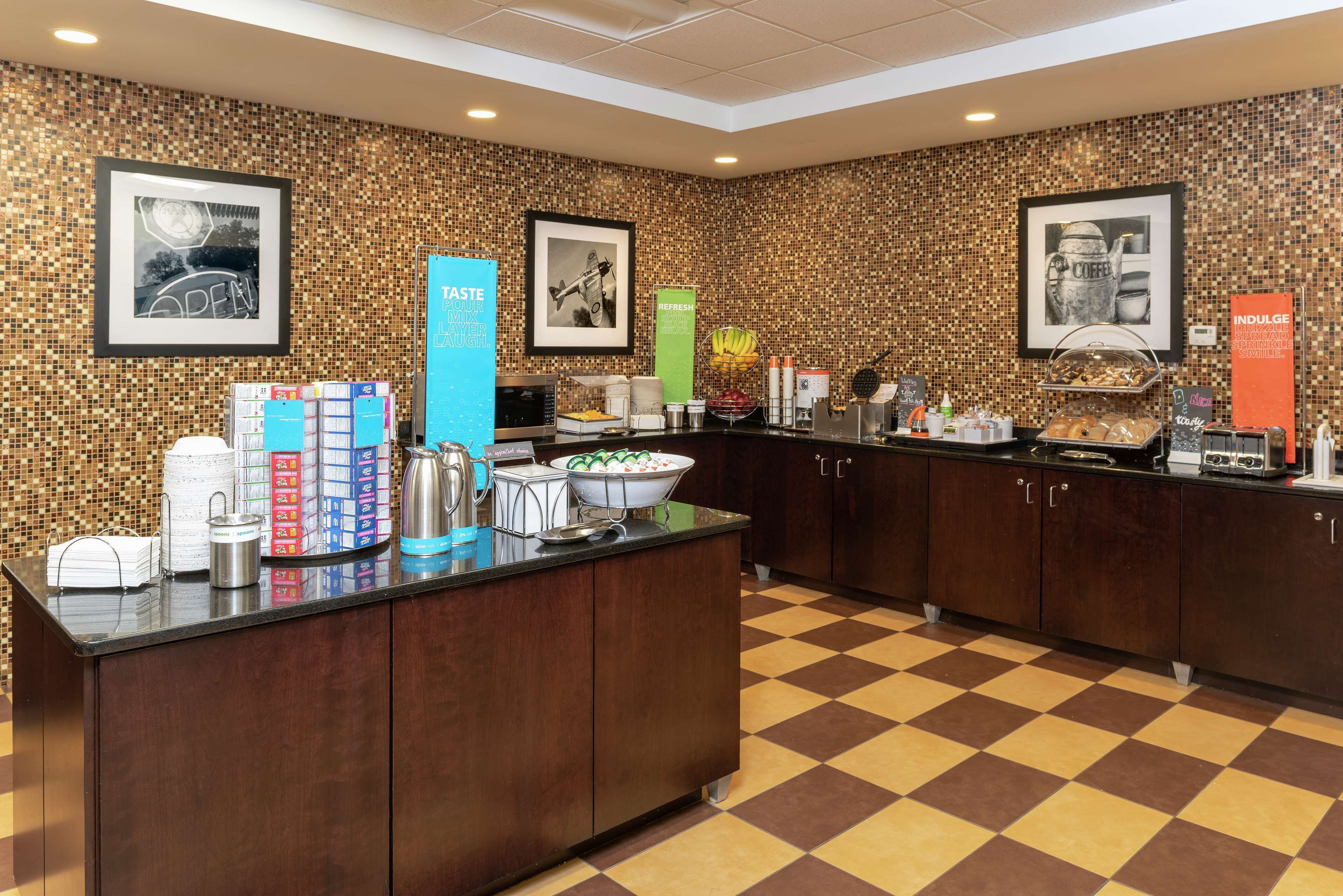 Um saguão de hotel com balcão de recepção, estação de café e área de buffet.