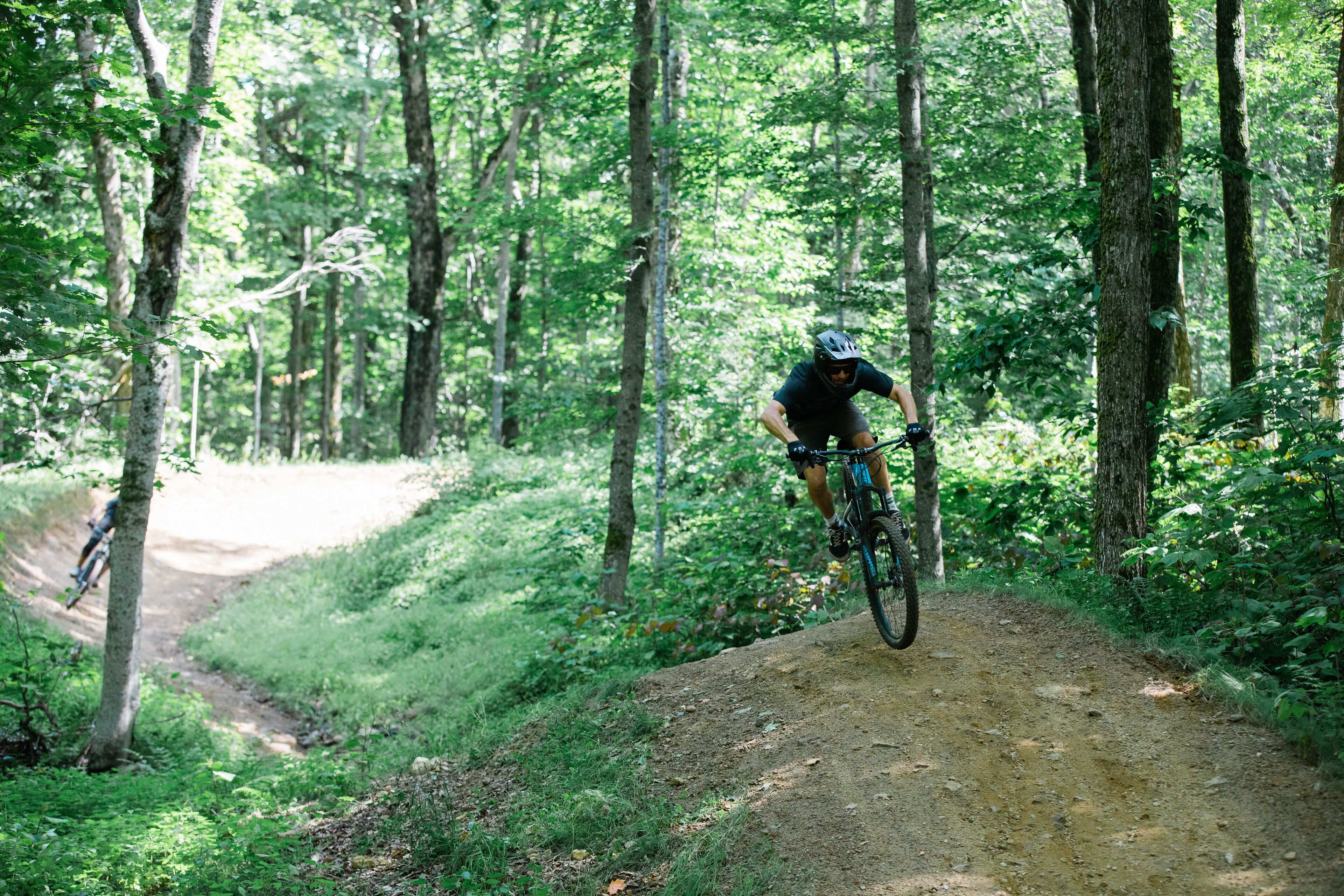 Ciclista de montanha numa trilha de terra rodeado por floresta densa.