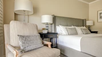 Quarto de hotel com cama, uma cadeira, mesa de cabeceira e duas luminárias.