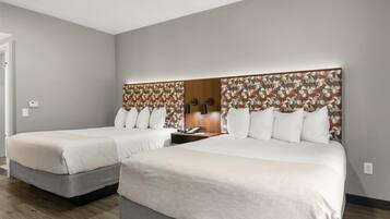 Quarto de hotel com duas camas de solteiro, cabeceira de madeira com padrão geométrico, mesa de cabeceira com abajur e telefone fixado na parede.