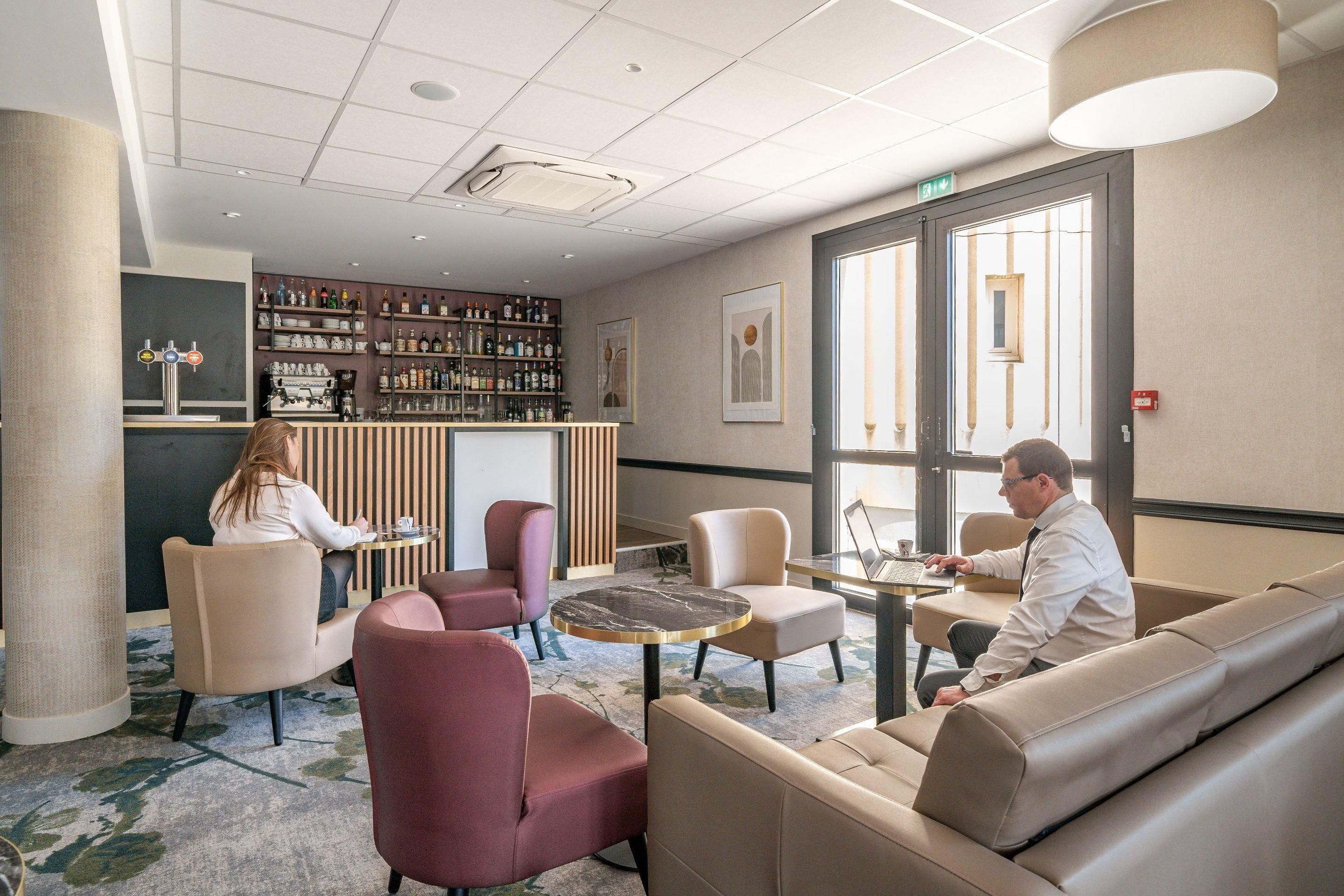 Espaço de estar moderno com assentos, bar e vista por uma porta de vidro.