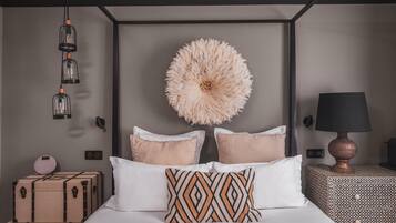 Quarto moderno com cama, almofadas decorativas, um enfeite de parede fofo, luminária e mesa de cabeceira.