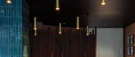 Uma área de estar moderna com sofá, duas poltronas, mesa de centro e iluminação pendente.
