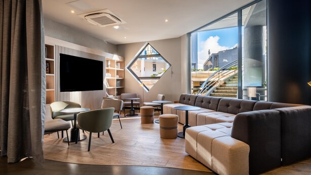 Uma área de estar moderna com um sofá grande, cadeiras, uma TV e uma estante.