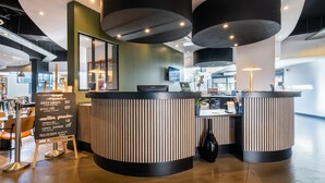 Interior moderno de café, com balcão, área de estar e quadro de cardápio.