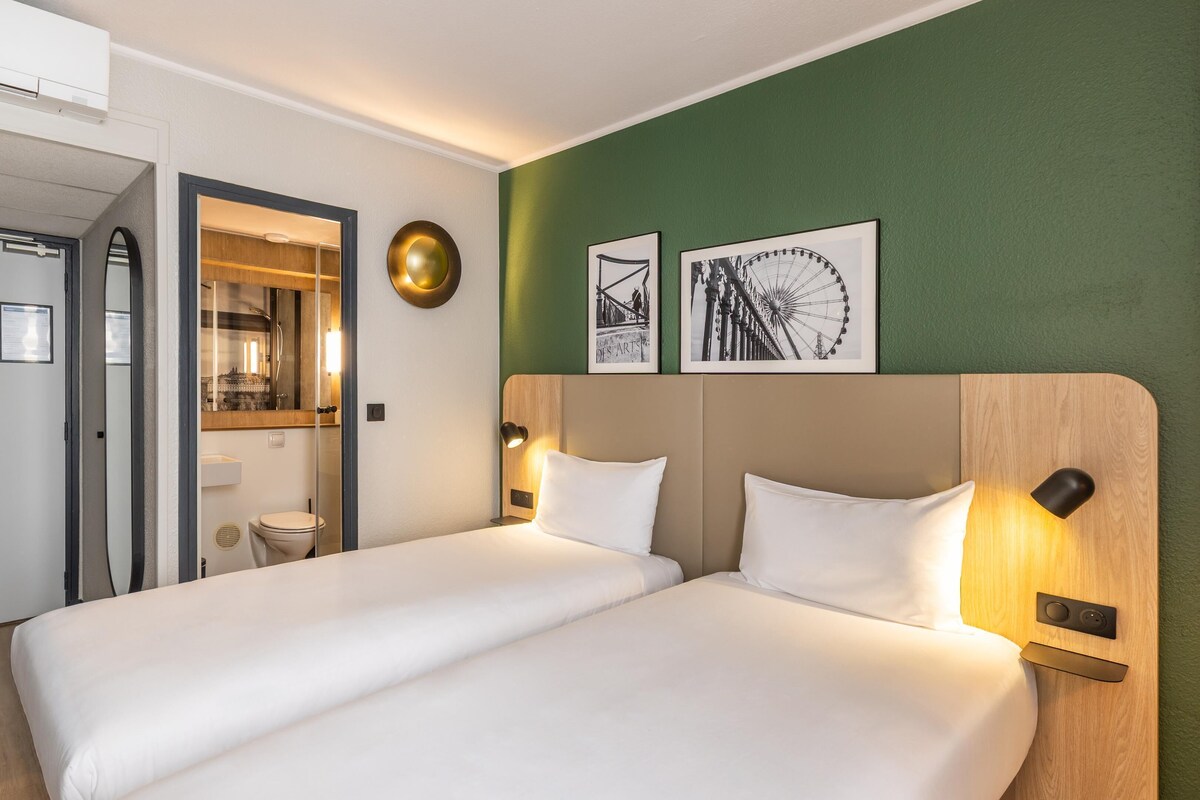 Quarto de hotel com cama, banheiro e parede verde.