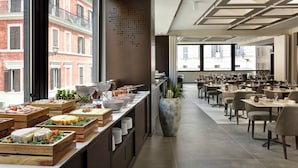 Uma área de refeições moderna com serviço de buffet, janelas amplas e vista para a cidade.