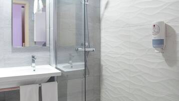 Uma casa de banho moderna com chuveiro envidraçado, pia e espelho.