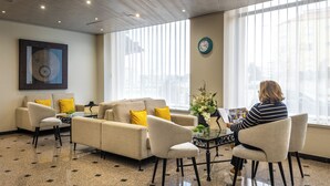 Uma sala de estar moderna com sofá, cadeiras, uma mesa de centro e uma janela grande com persianas.