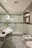 Uma casa de banho moderna com chuveiro em cabine de vidro, lavatório duplo e bidé.