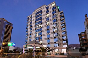 Um hotel de vários andares com a placa Holiday Inn Express, rodeado por outros edifícios.
