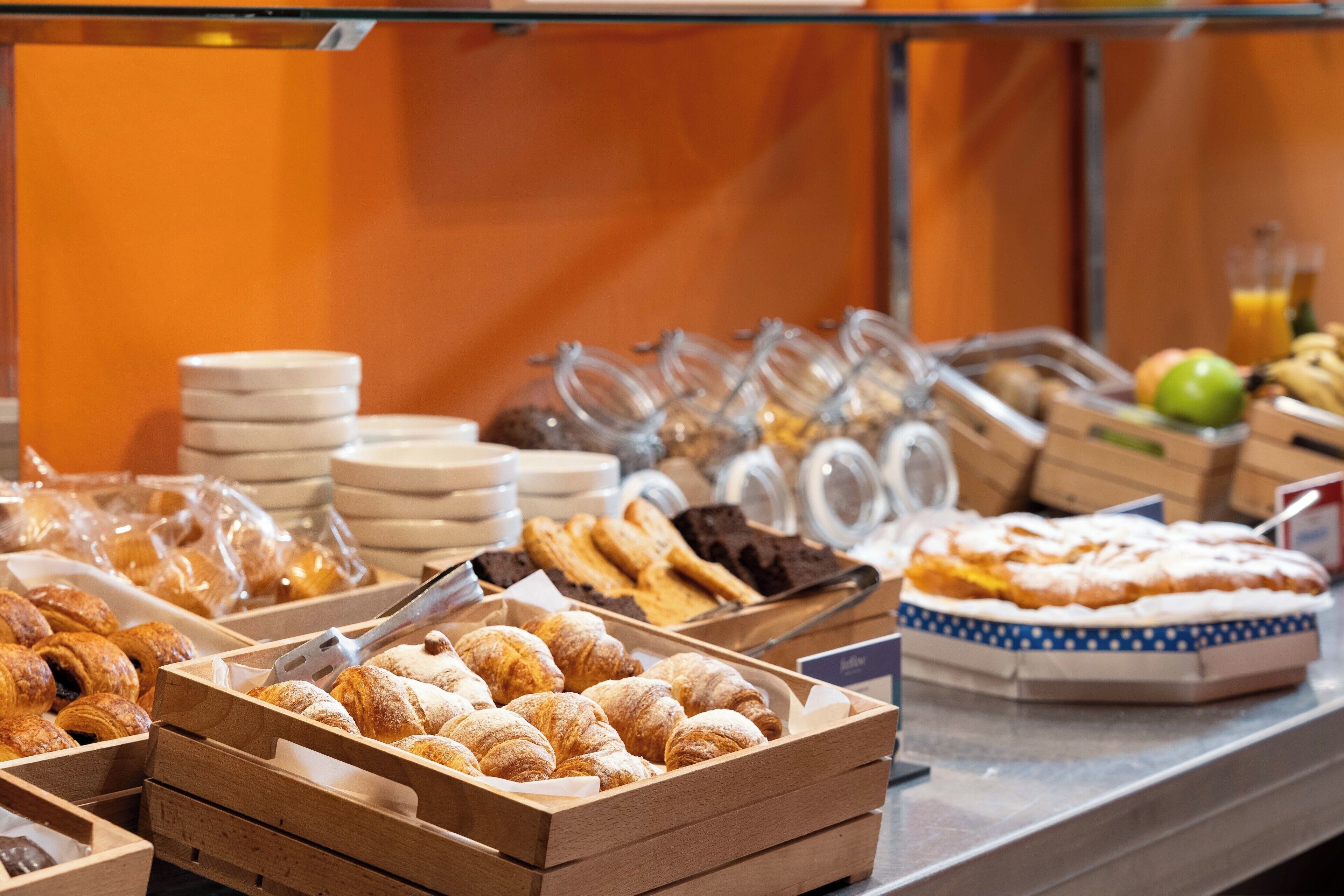 Um buffet de café da manhã com diversos pães e frutas.