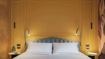 Quarto de hotel com uma cama grande, duas mesas de cabeceira, luminária fixada na parede e painel decorativo.