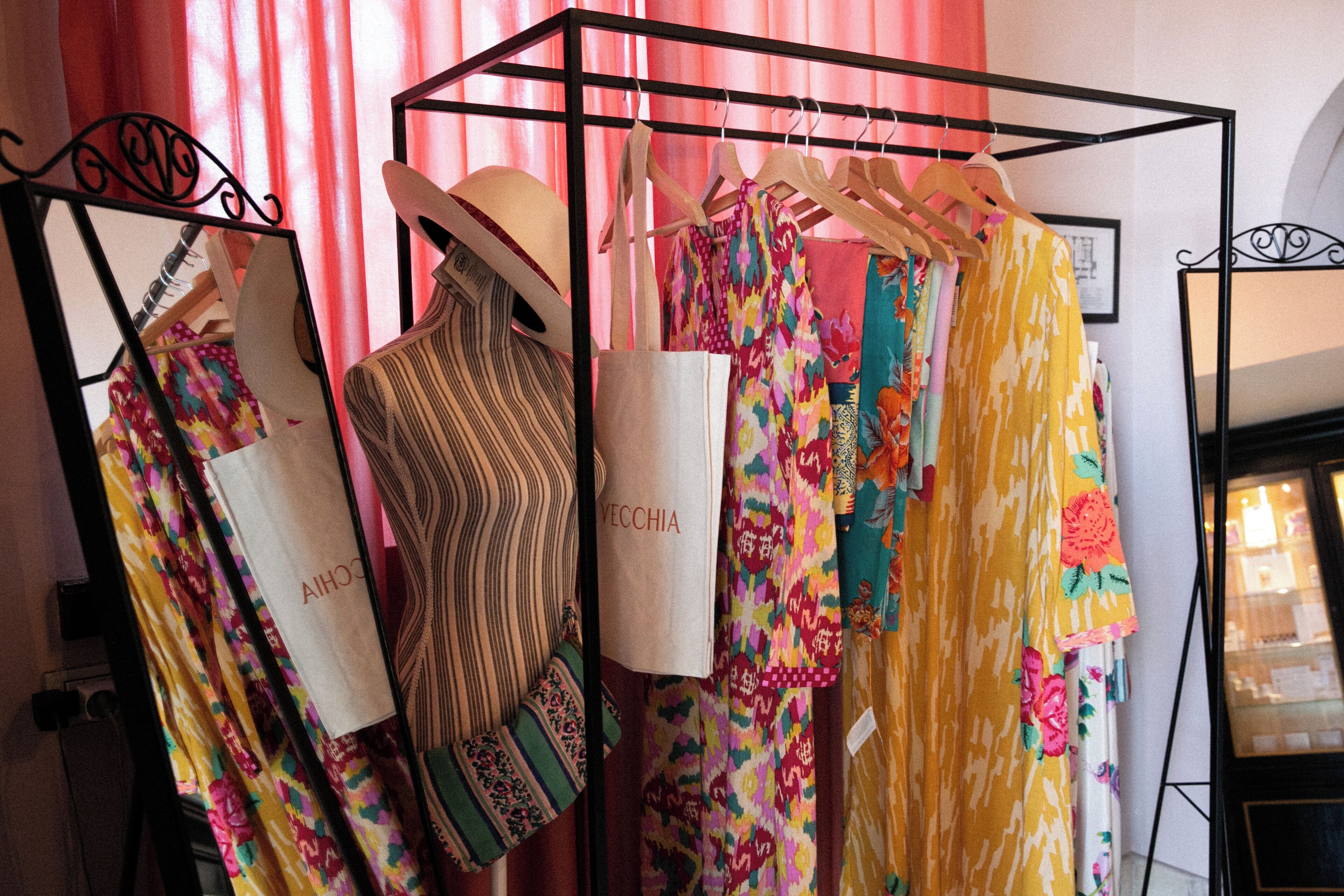 Um cabideiro com várias peças de roupa e um manequim.