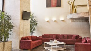 Um hall amplo com um lustre moderno, uma grande pintura abstrata e uma escadaria curva.