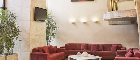 Um hall amplo com um lustre moderno, uma grande pintura abstrata e uma escadaria curva.