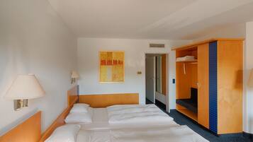 Quarto de hotel com uma cama grande, um guarda-roupa de madeira e um quadro na parede.