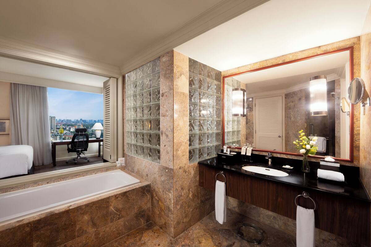 Uma casa de banho moderna com banheira, toucador com espelho e vista para a cidade.