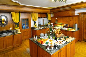 Uma cozinha espaçosa com armários de madeira, bancada de mármore e diversos alimentos e temperos.