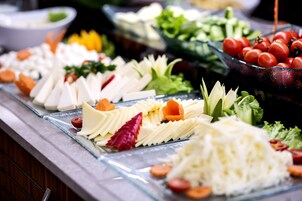 Buffet com diversos alimentos, incluindo carnes fatiadas, queijos e legumes.