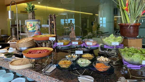 Buffet com diversas opções de comida, incluindo frutas frescas, saladas e patês.