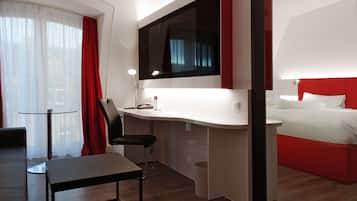 Quarto de hotel moderno com escrivaninha, cadeira e cama.
