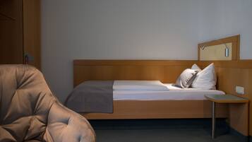 Um quarto com uma cama de madeira, uma pequena mesa de cabeceira, uma cadeira e um guarda-roupa.