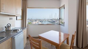 Cozinha compacta com vista para uma marina, uma mesa de jantar e cadeiras de madeira.