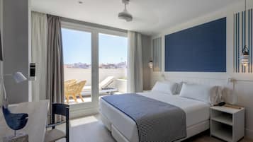Quarto de hotel moderno com uma cama grande, uma escrivaninha e uma cadeira. Possui uma varanda com vista para a cidade.