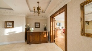 Um corredor com mesa consola de madeira, quadros, candelabro e um espelho grande.