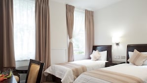 Quarto de hotel com duas camas, uma mesa de jantar e uma cadeira.