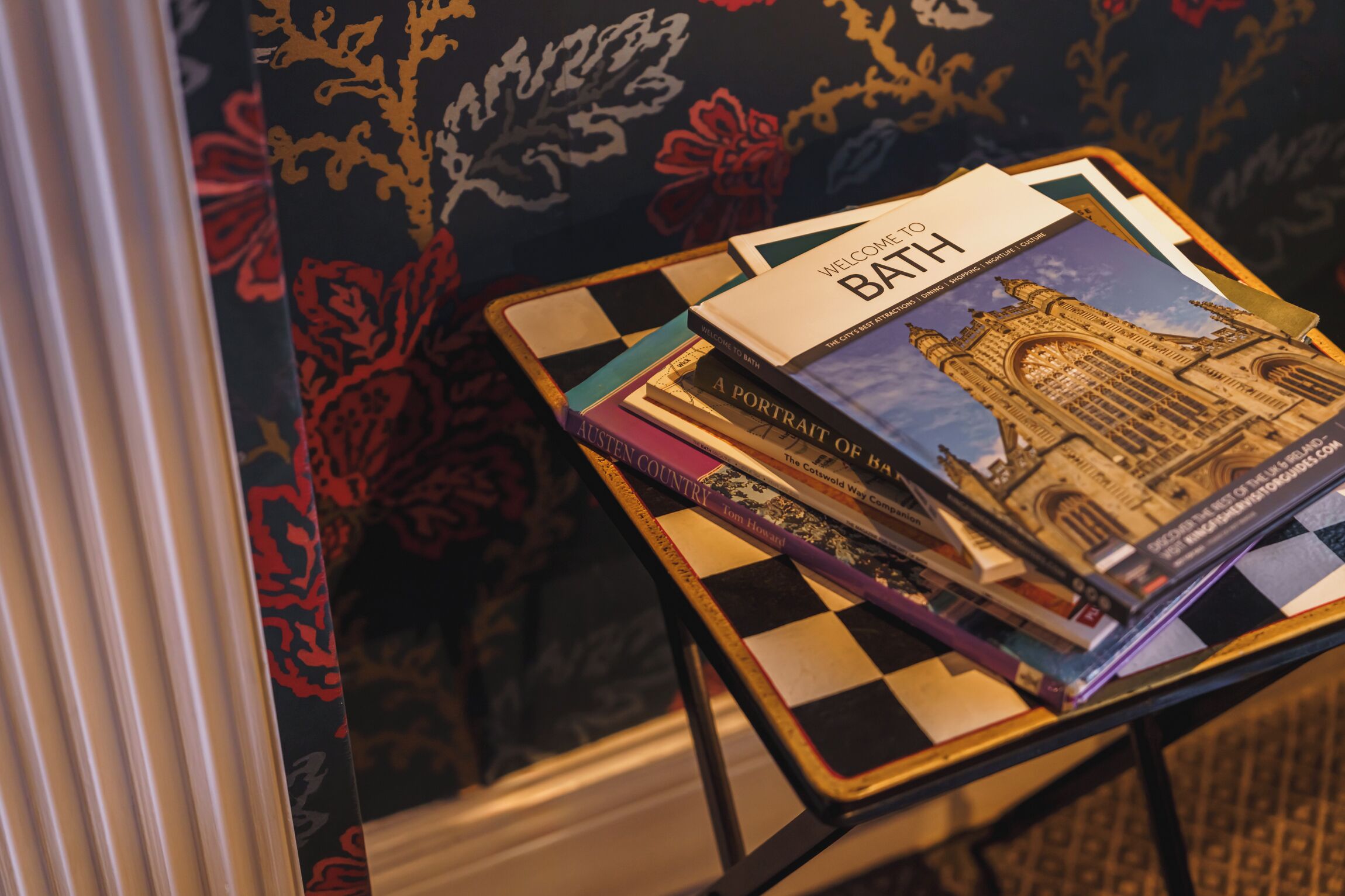 Uma pilha de livros sobre uma mesa com padrão xadrez, incluindo títulos como 