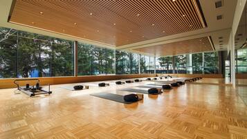 Quarto amplo com grandes janelas, piso de madeira e equipamentos de ginástica.
