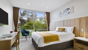 Quarto de hotel moderno com uma cama grande, uma escrivaninha, uma cadeira e uma televisão.