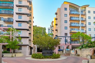 Um edifício residencial com vários andares, varandas, um pátio ajardinado e um aviso indicando serviços como restaurante e spa.
