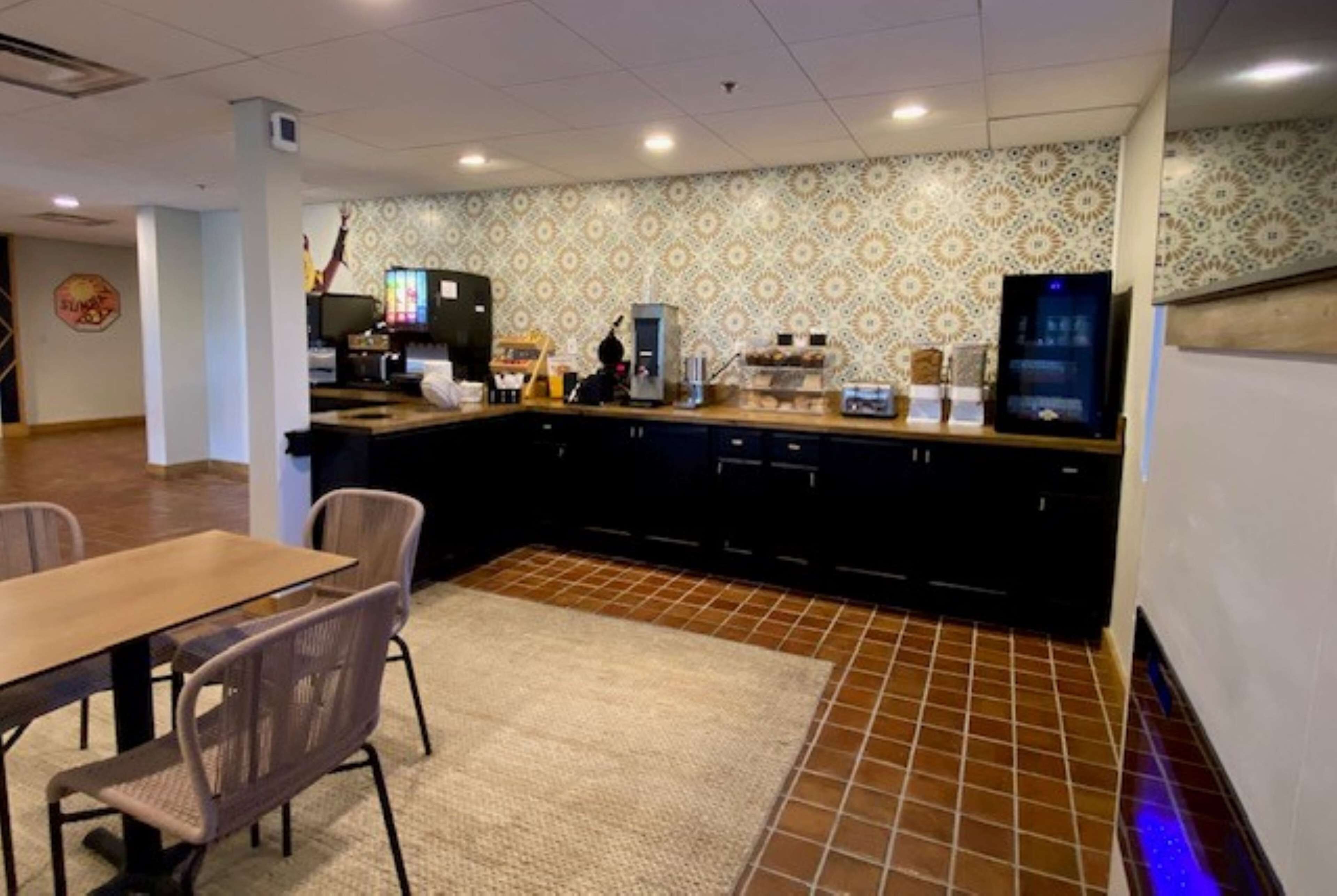 Cozinha moderna com armários escuros, painel de azulejos e uma cafeteira.