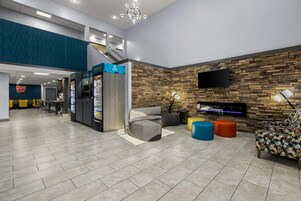 Um hall amplo com área de estar, estação de refrescos e uma parede de pedra com TV fixada.