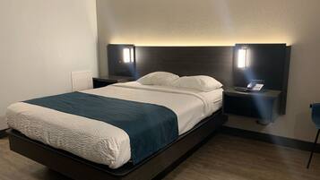 Quarto de hotel moderno com uma cama grande, duas mesas de cabeceira, televisão de tela plana e iluminação embutida na parede.
