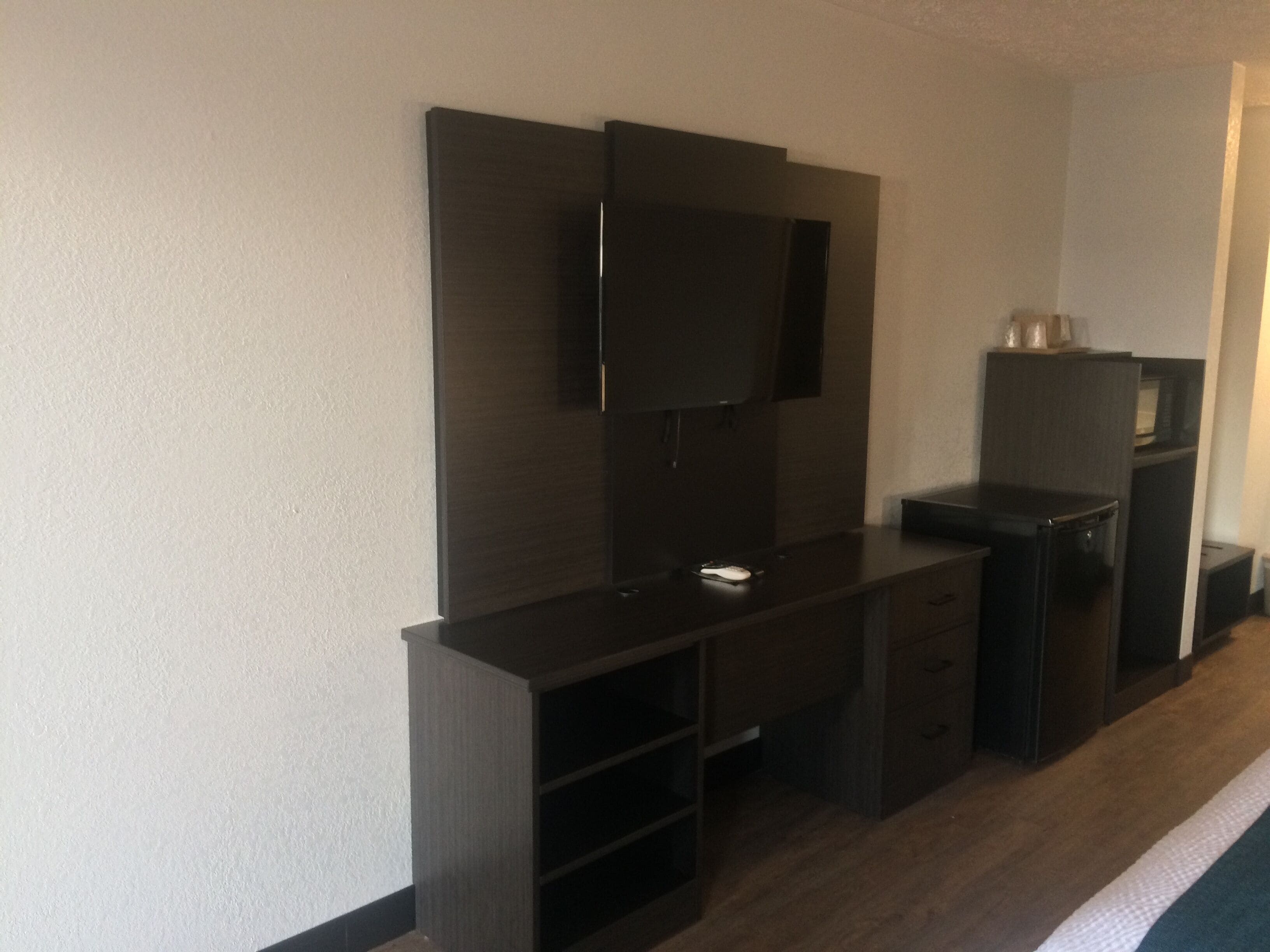Uma sala de estar moderna com uma TV de tela plana fixada em uma parede de madeira escura, um pequeno armário e um painel de entretenimento embutido.