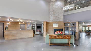 Um hall amplo com balcão de recepção, escadaria e área de refeições.