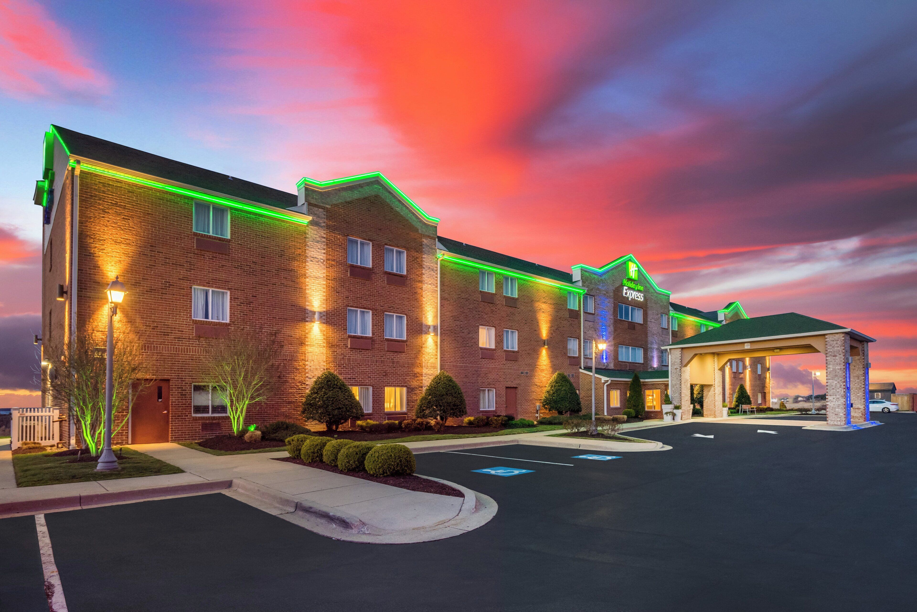 Um hotel Holiday Inn Express com fachada de tijolos, várias janelas e um estacionamento.