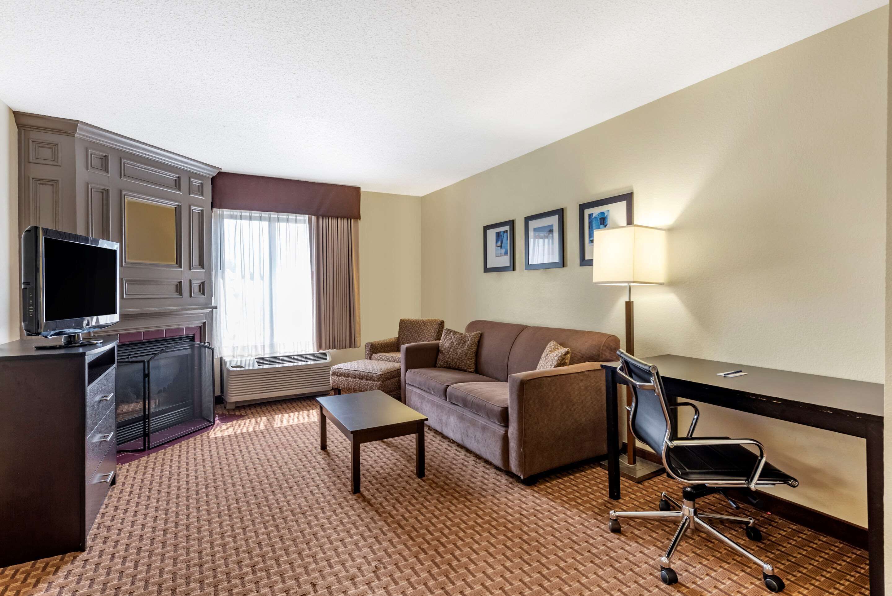 Quarto de hotel com televisão de tela plana, sofá, escrivaninha e uma cadeira.