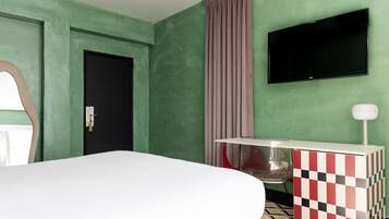 Quarto de hotel com uma cama, televisão presa na parede, um espelho e um armário xadrez.