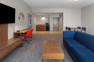 Uma sala de estar moderna com um sofá, uma mesa de centro, uma TV e um espaço de jantar com cadeiras e uma mesa.