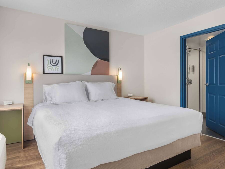 Quarto bem arrumado com uma cama grande, mesas de cabeceira e uma porta azul.
