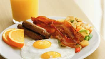 Prato de comida de café da manhã com ovos, bacon, salsichas e batatas palha.