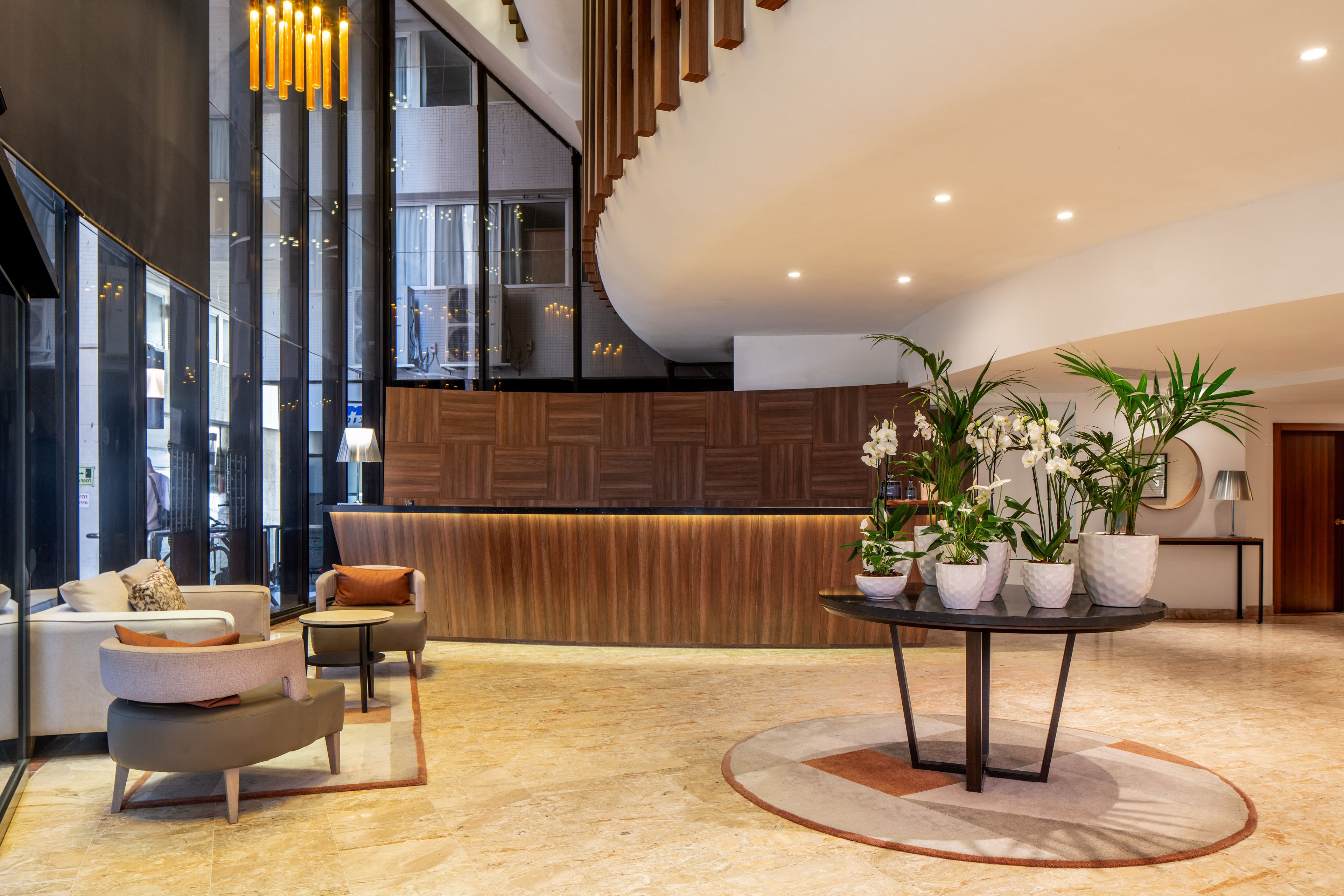 Um lobby moderno com balcão de recepção, área de estar e plantas em vasos.