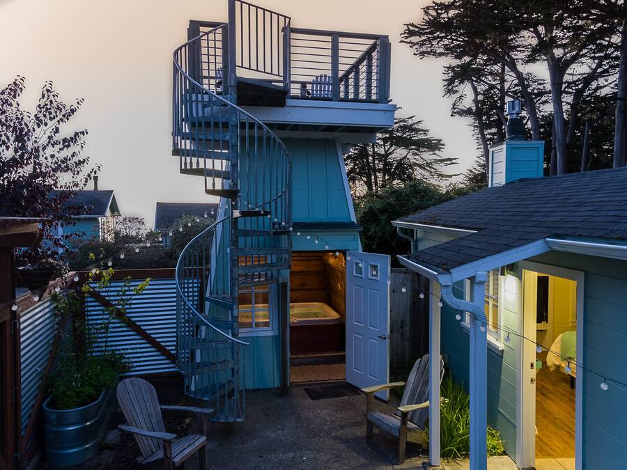 Uma casa azul de dois andares com uma escada em caracol que dá para uma varanda.